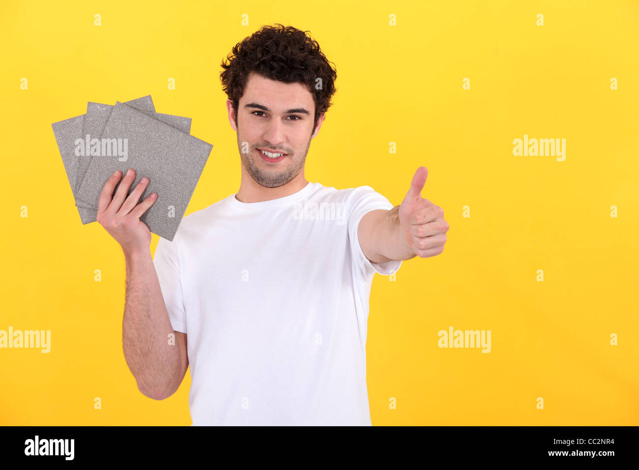 Man holding tiles on yellow background Stock Photo - Alamy