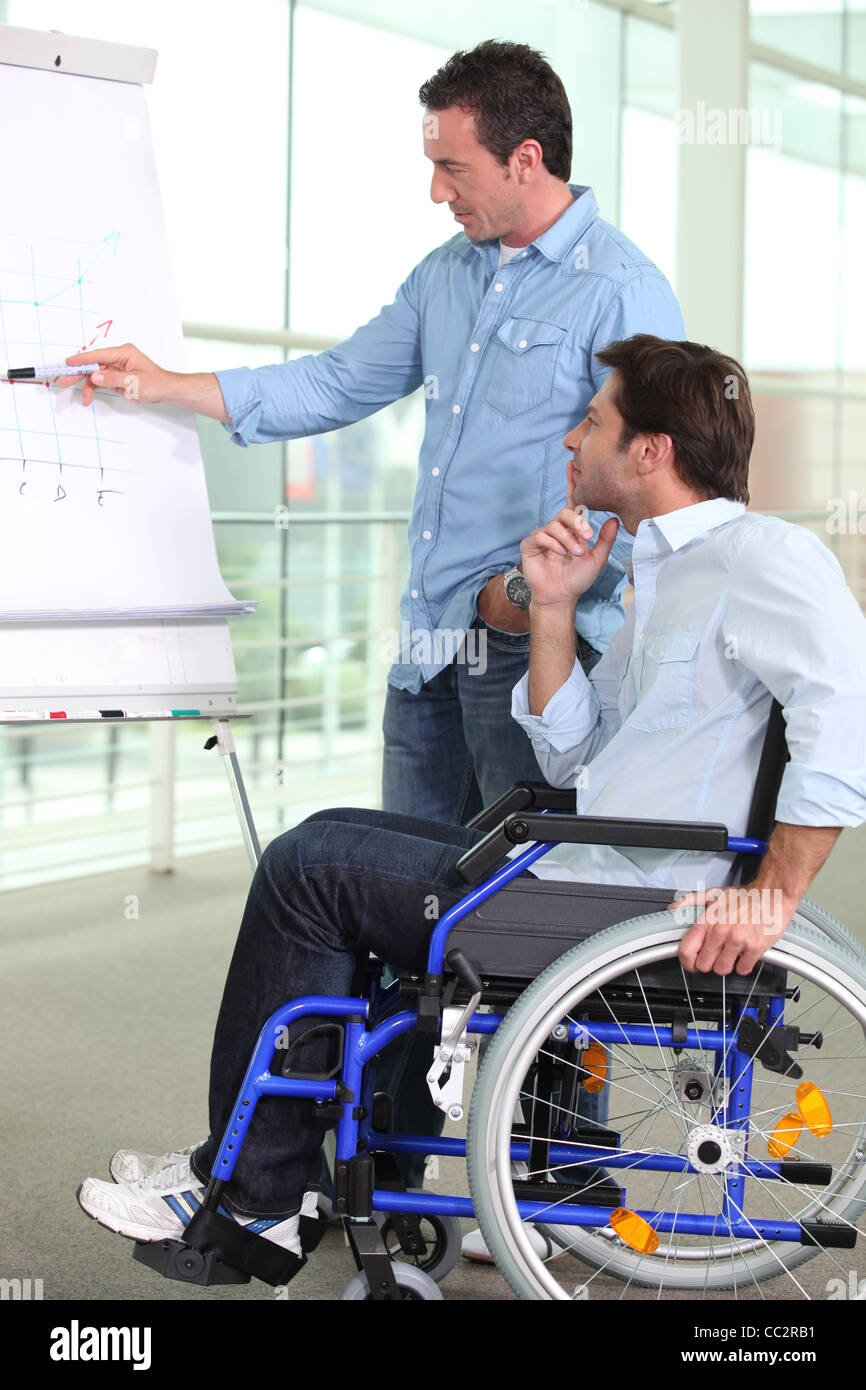 An employee pointing at a board and explaining something to a male ...