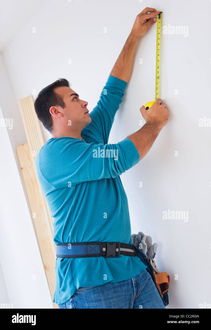 Construction worker measuring wall Stock Photo - Alamy