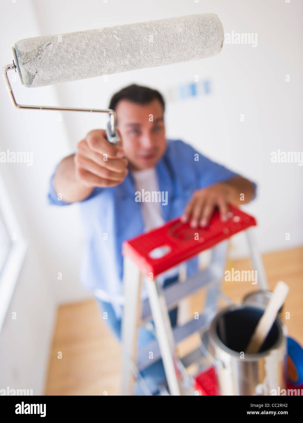 Man standing on ladder with paint roller Stock Photo - Alamy