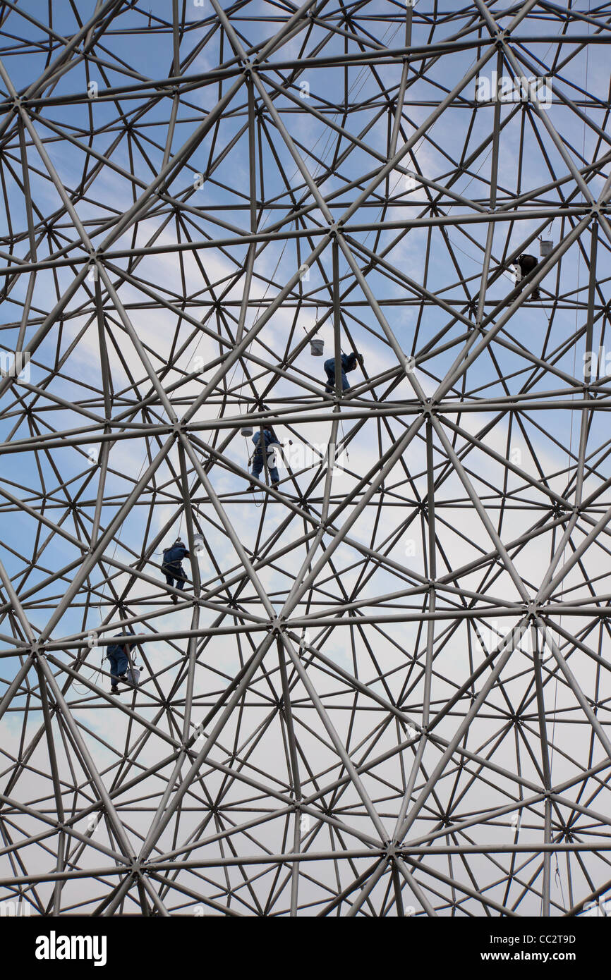 5 climbers on a metallic net structure painting. the illusion that they ...