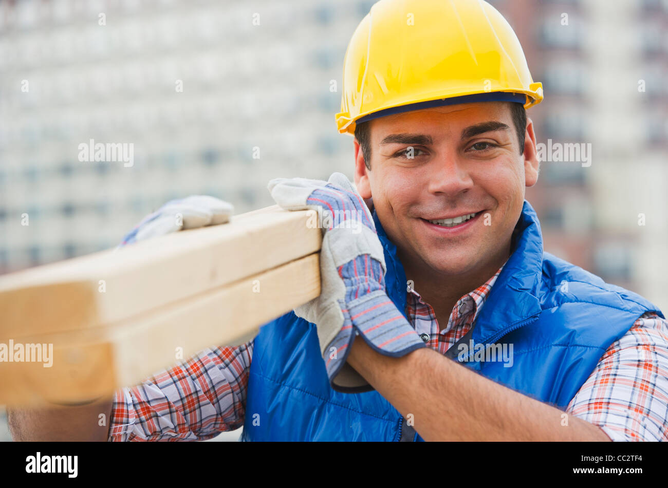 USA, New Jersey, Jersey City, Construction worker carrying planks on ...