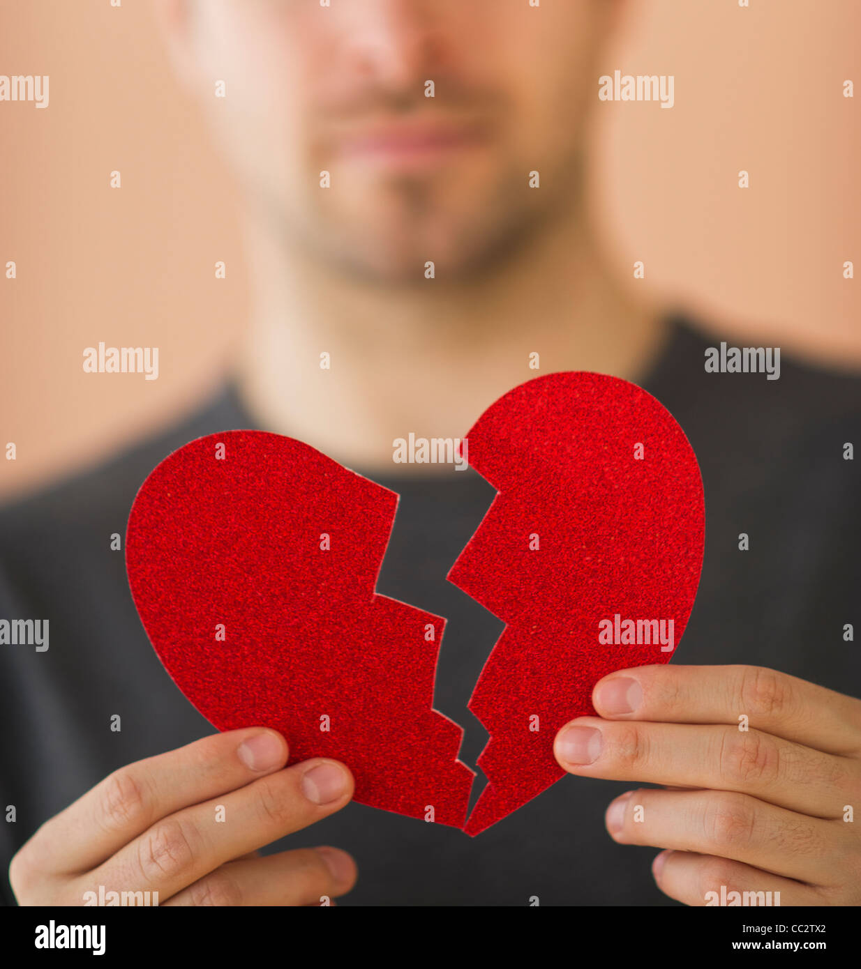 Young man holding broken paper heart Stock Photo - Alamy