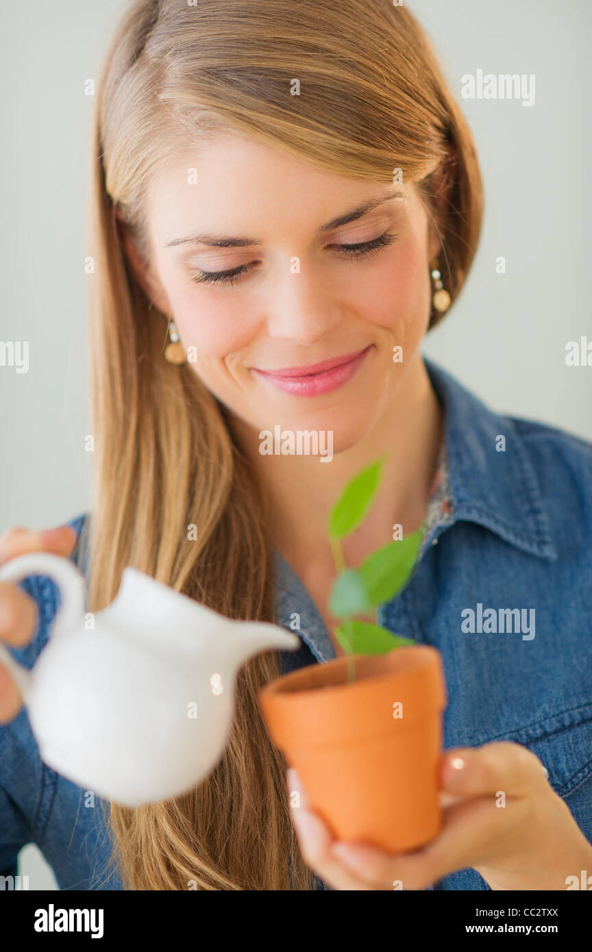Young woman watering small plant Stock Photo - Alamy