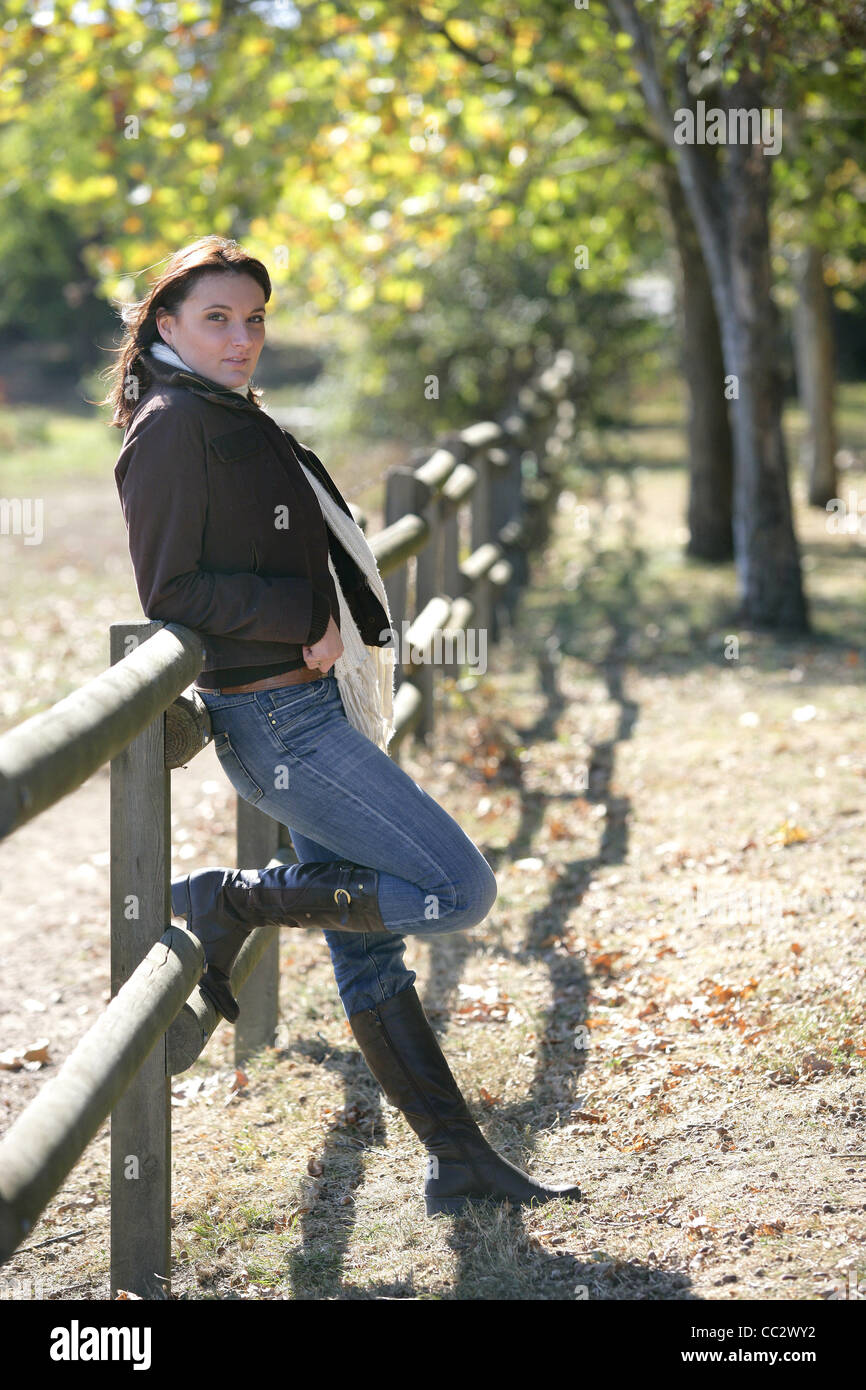 Woman leaning against wooden fence Stock Photo - Alamy