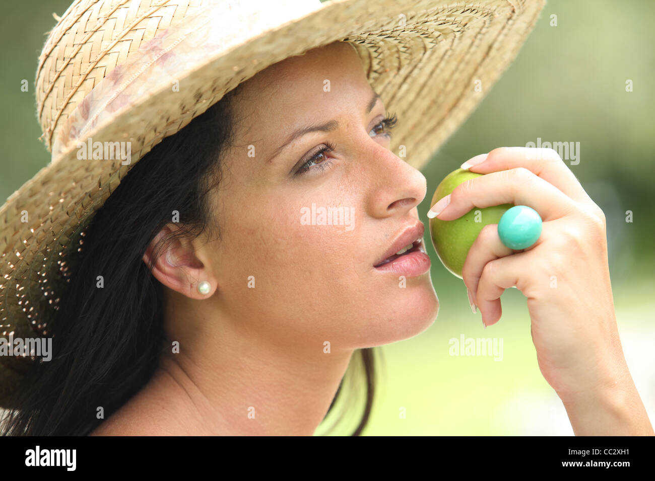 Woman in a straw hat about to bite an apple Stock Photo - Alamy