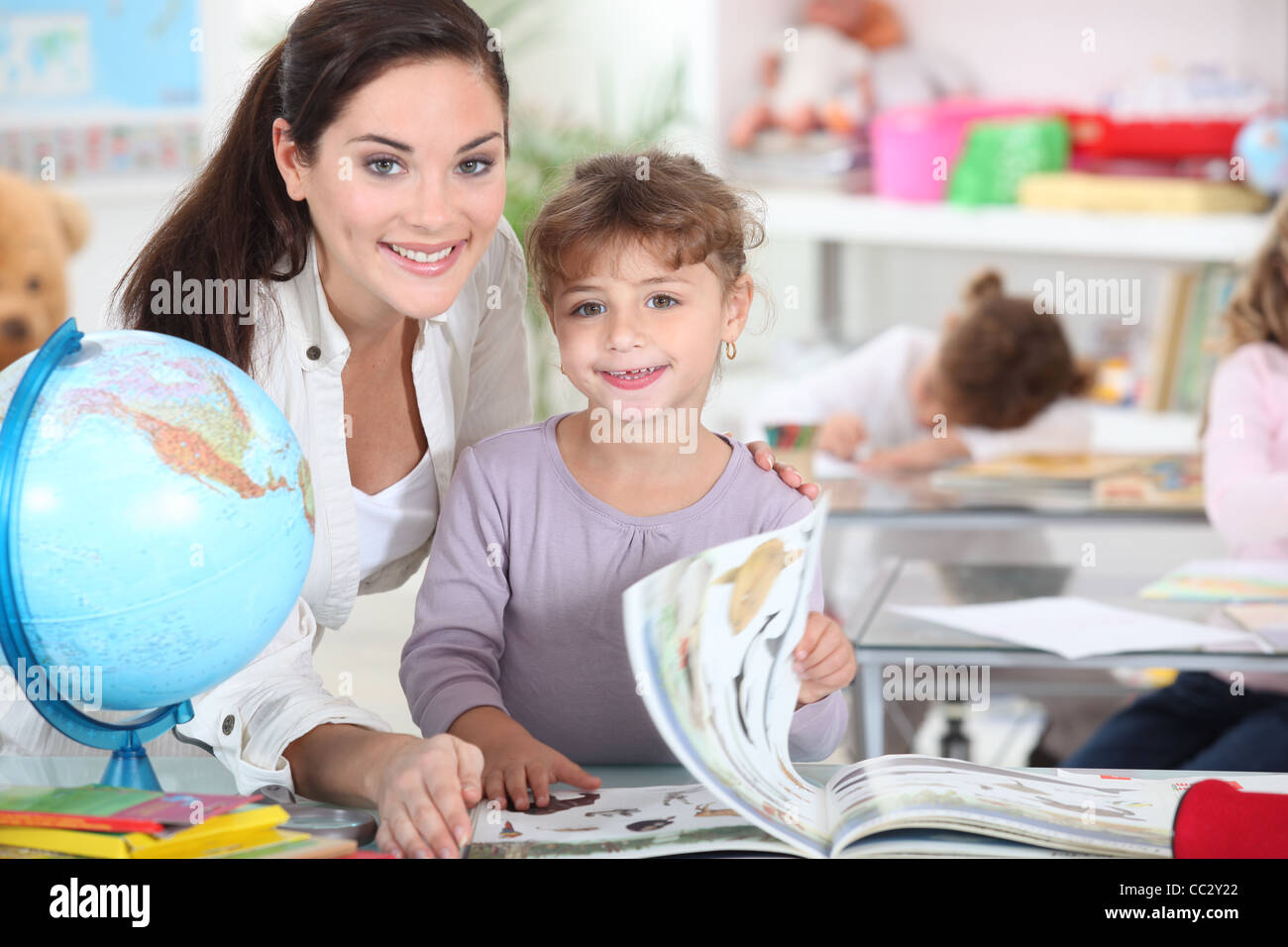 a female teacher and a little girl in a classroom Stock Photo - Alamy