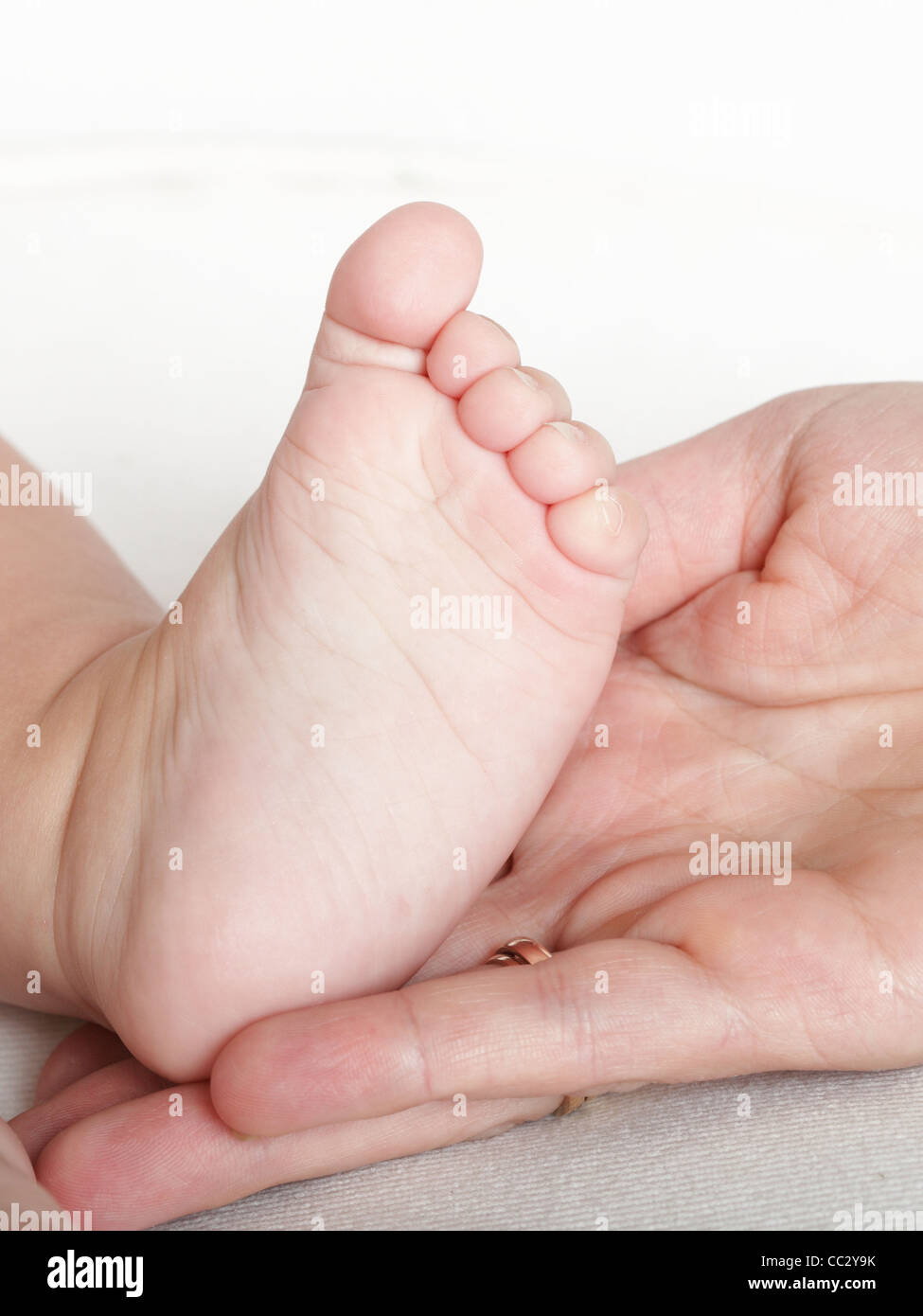 Baby foot in mother hands on white background Stock Photo - Alamy