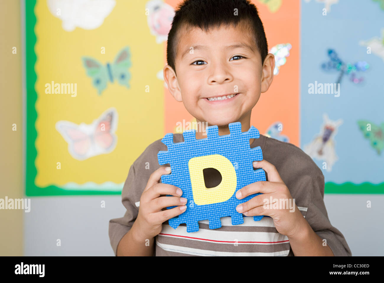 USA, California, Los Angeles, Boy (6-7) holding D letter in classroom ...