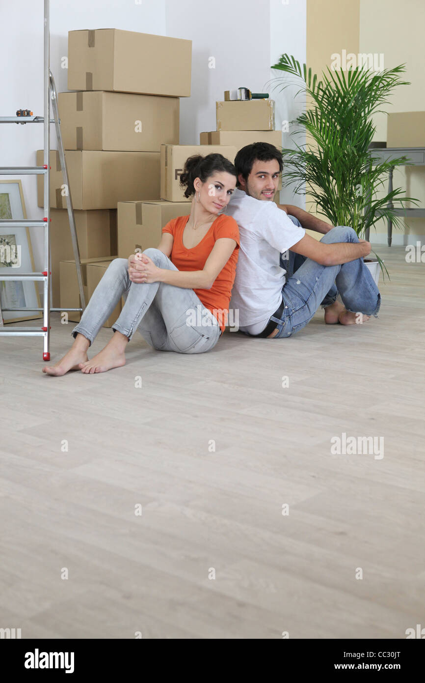 Couple sat back to back on floor Stock Photo - Alamy