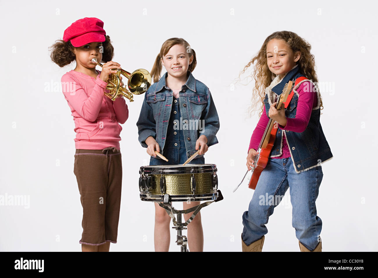 Three girls (8-9) playing instruments together, studio shot Stock Photo ...
