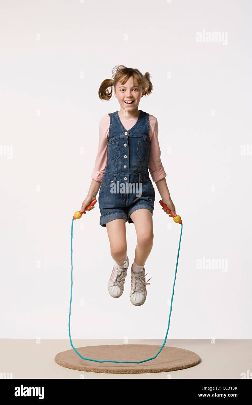 Studio portrait of girl (8-9) jumping on rope Stock Photo - Alamy