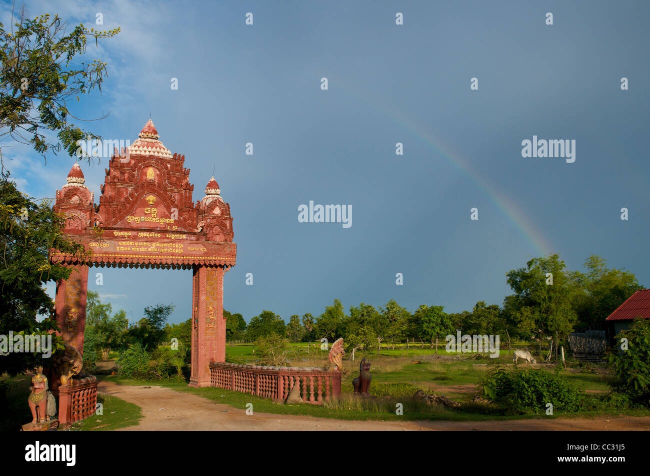 Rainbow over sunlit Buddhist temple gate w/ Khmer script, Kampot ...