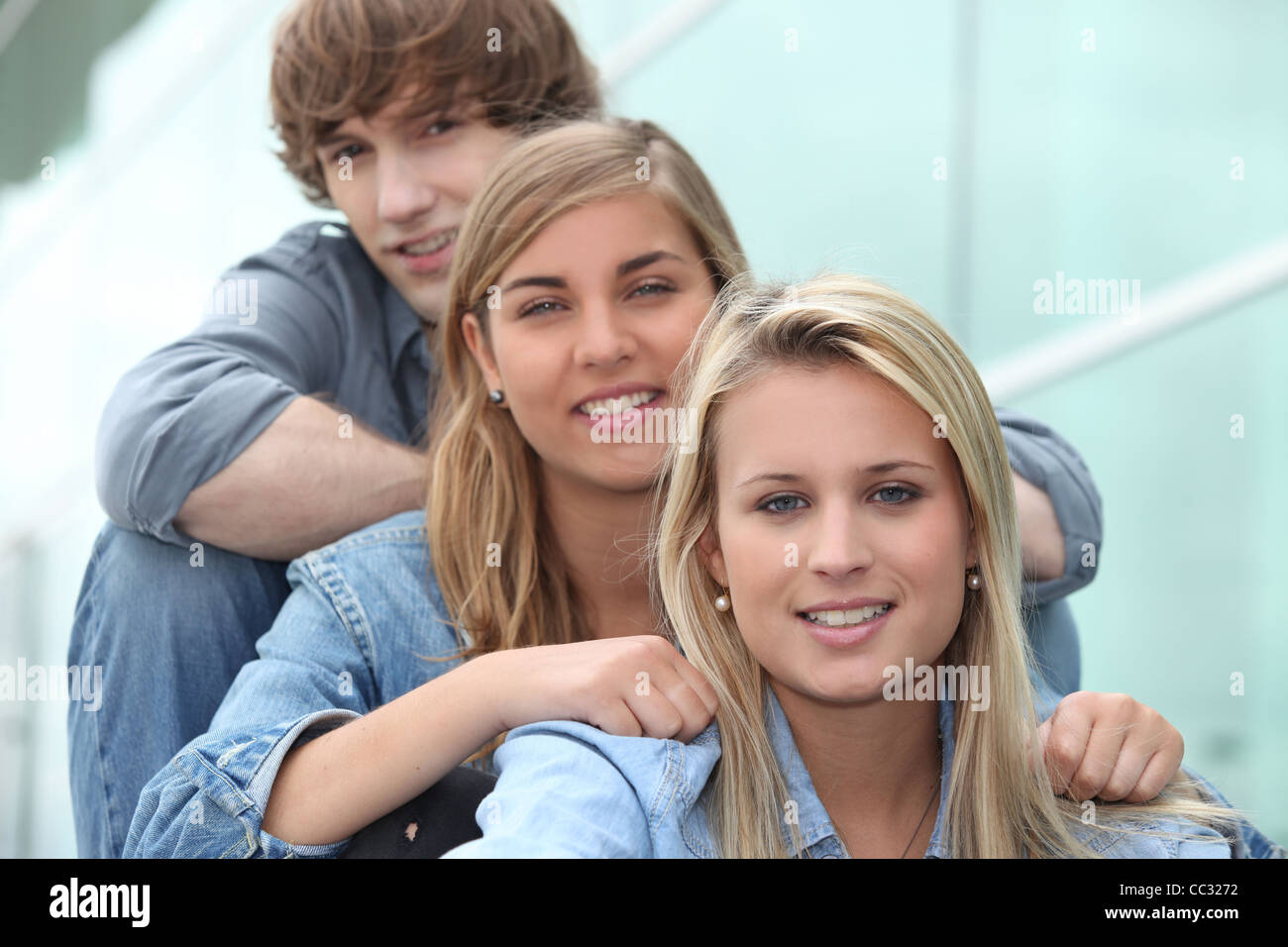 three students sitting in line Stock Photo - Alamy