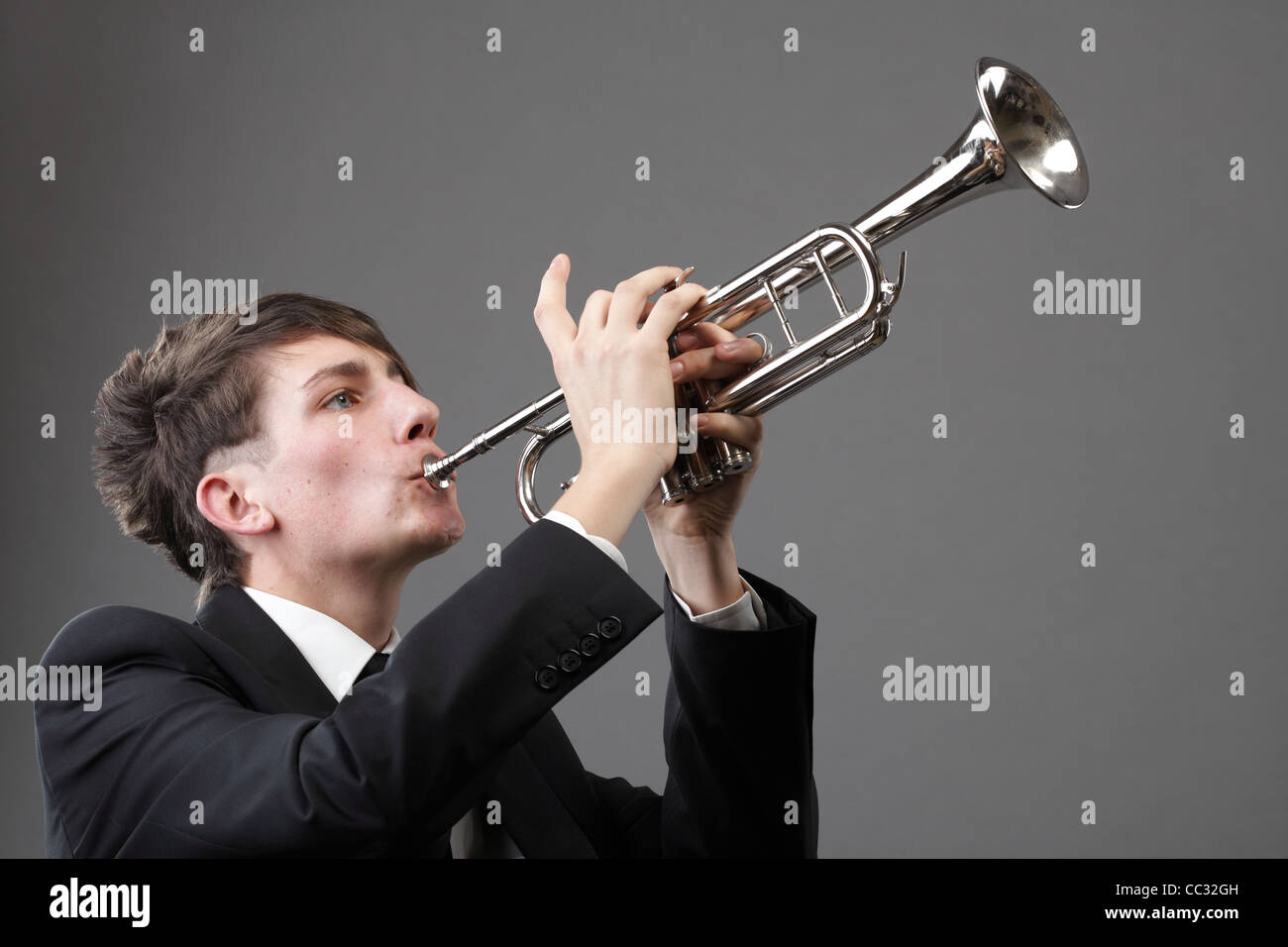 Portrait of a young jazz man playing his Trumpet grey background Stock ...