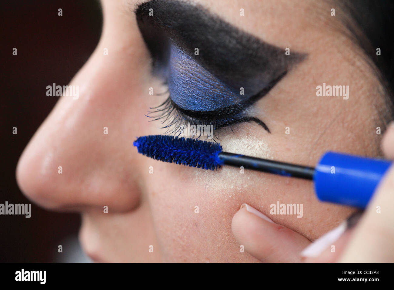 Charming young woman applying blusher eyelid close up blue Stock Photo ...