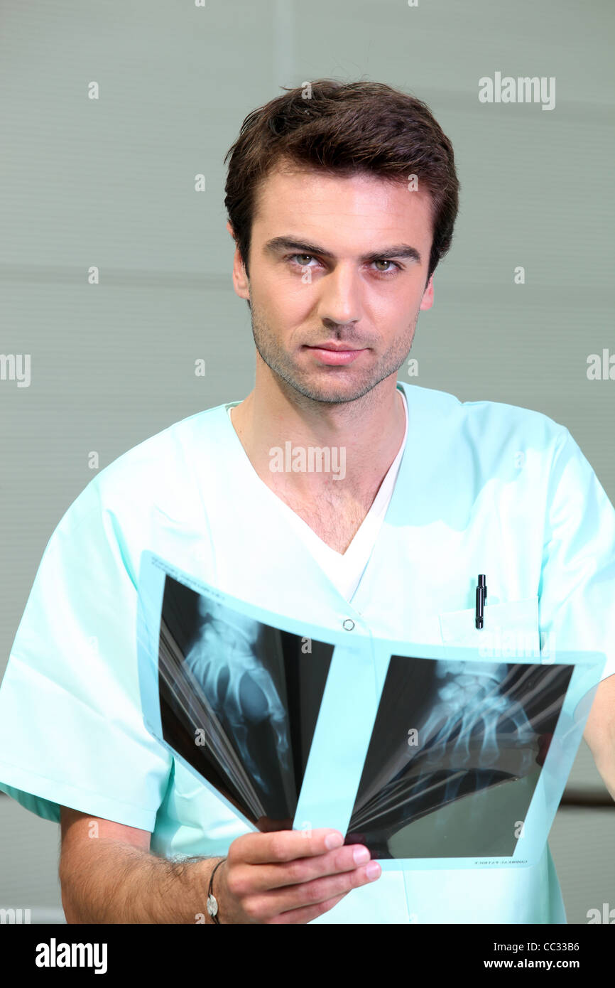 Medic in scrubs looking at the xray of a hand Stock Photo - Alamy