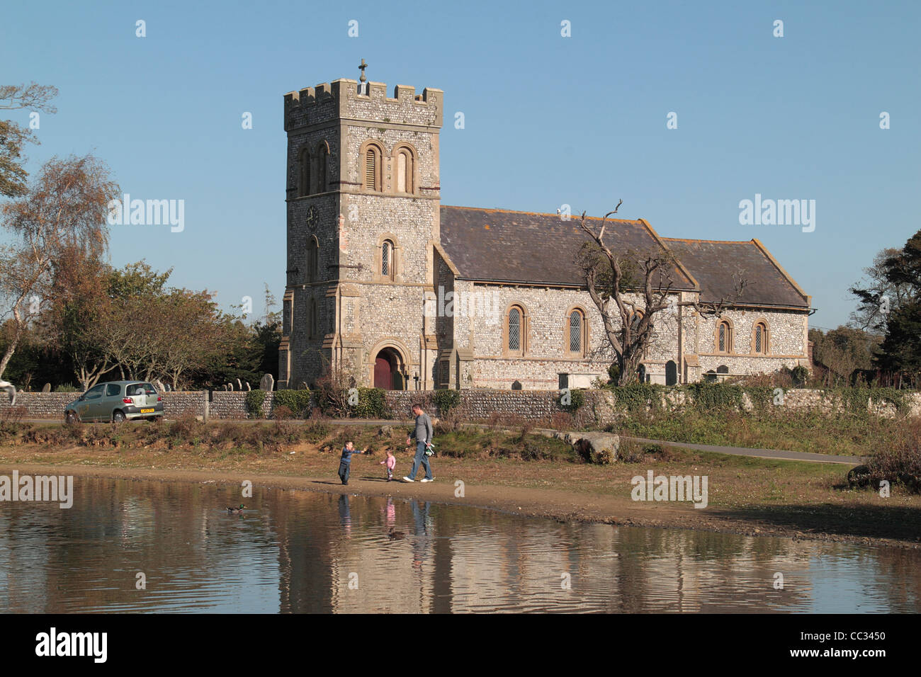 A family beside the village pond with St Laurence church behind in the ...
