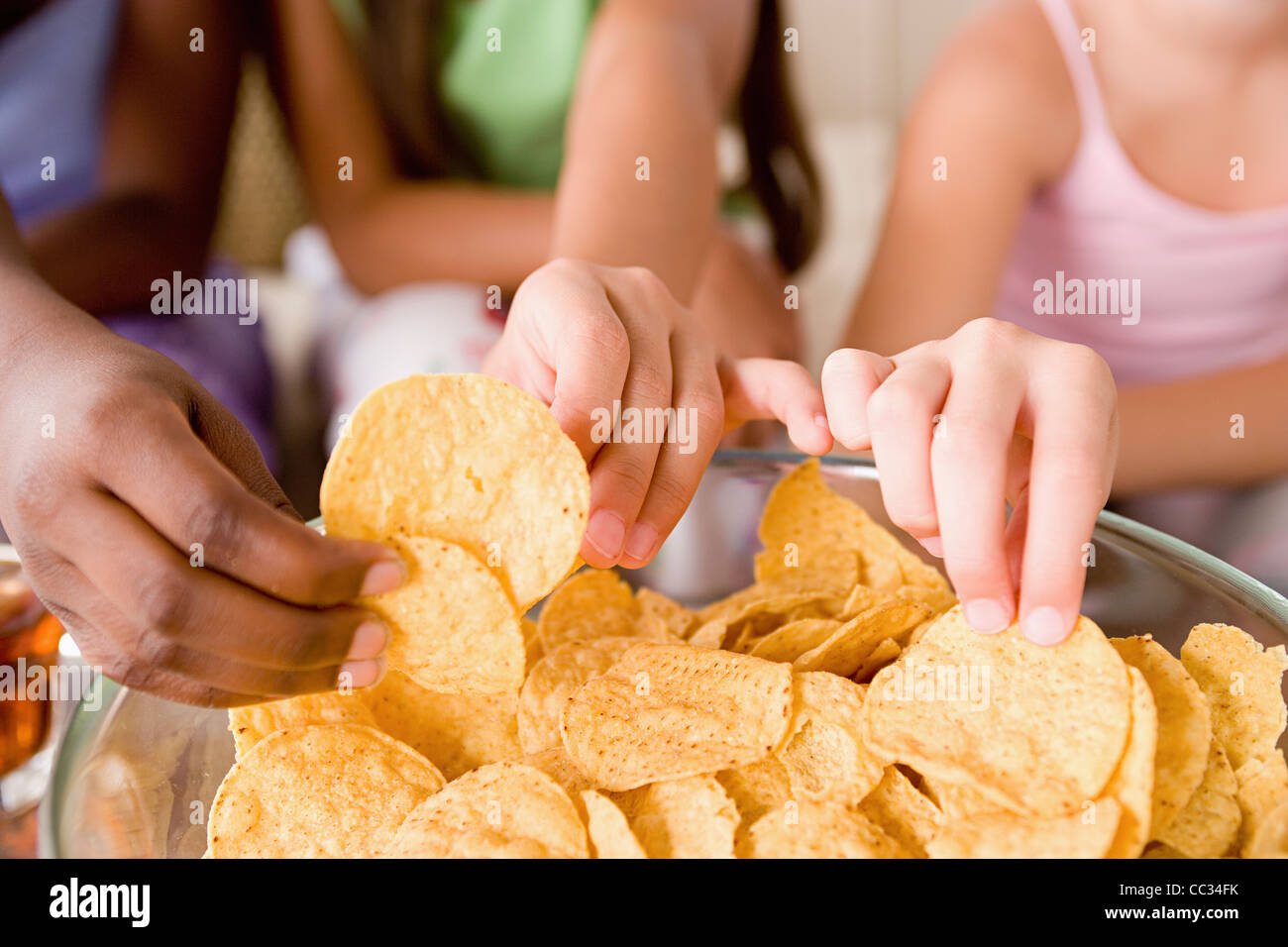 USA, California, Los Angeles, Three girls (10-11) reaching for crisps ...