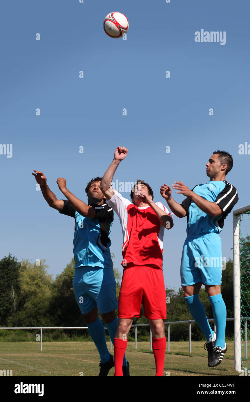 Footballers jumping for ball Stock Photo - Alamy