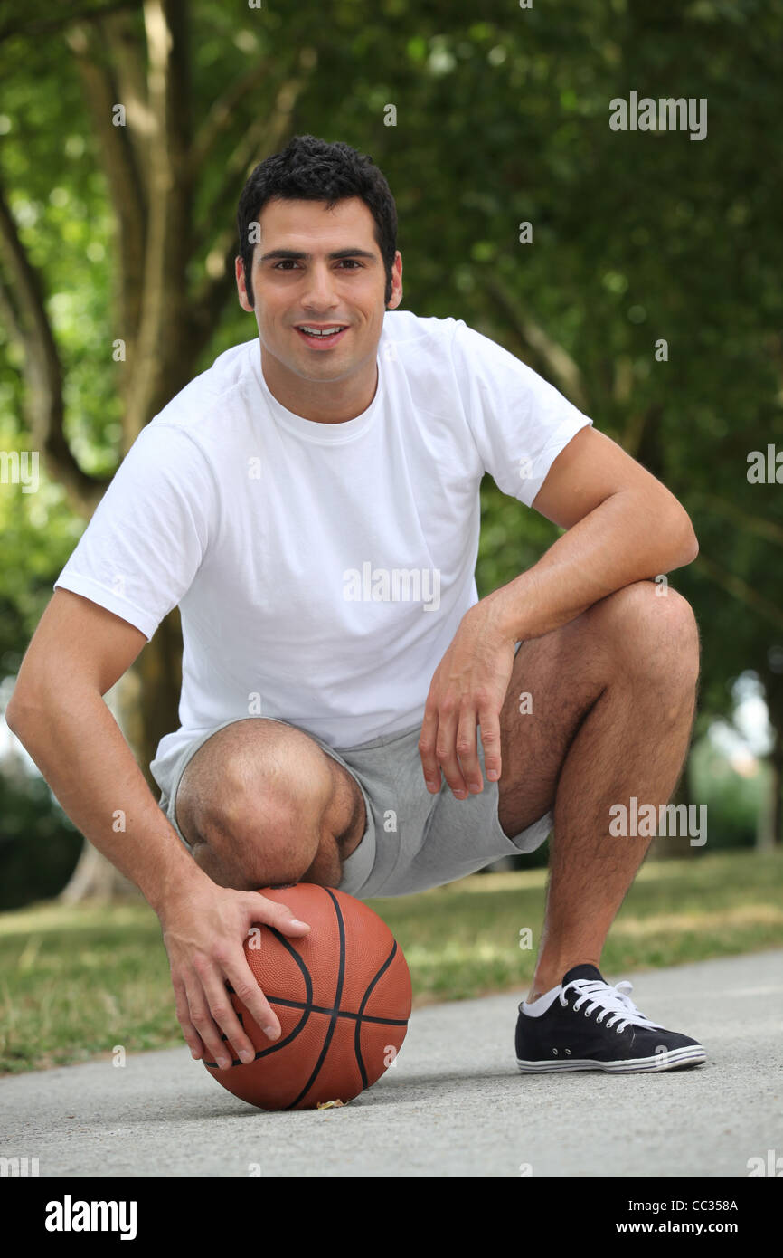 Man crouching with basket ball Stock Photo - Alamy