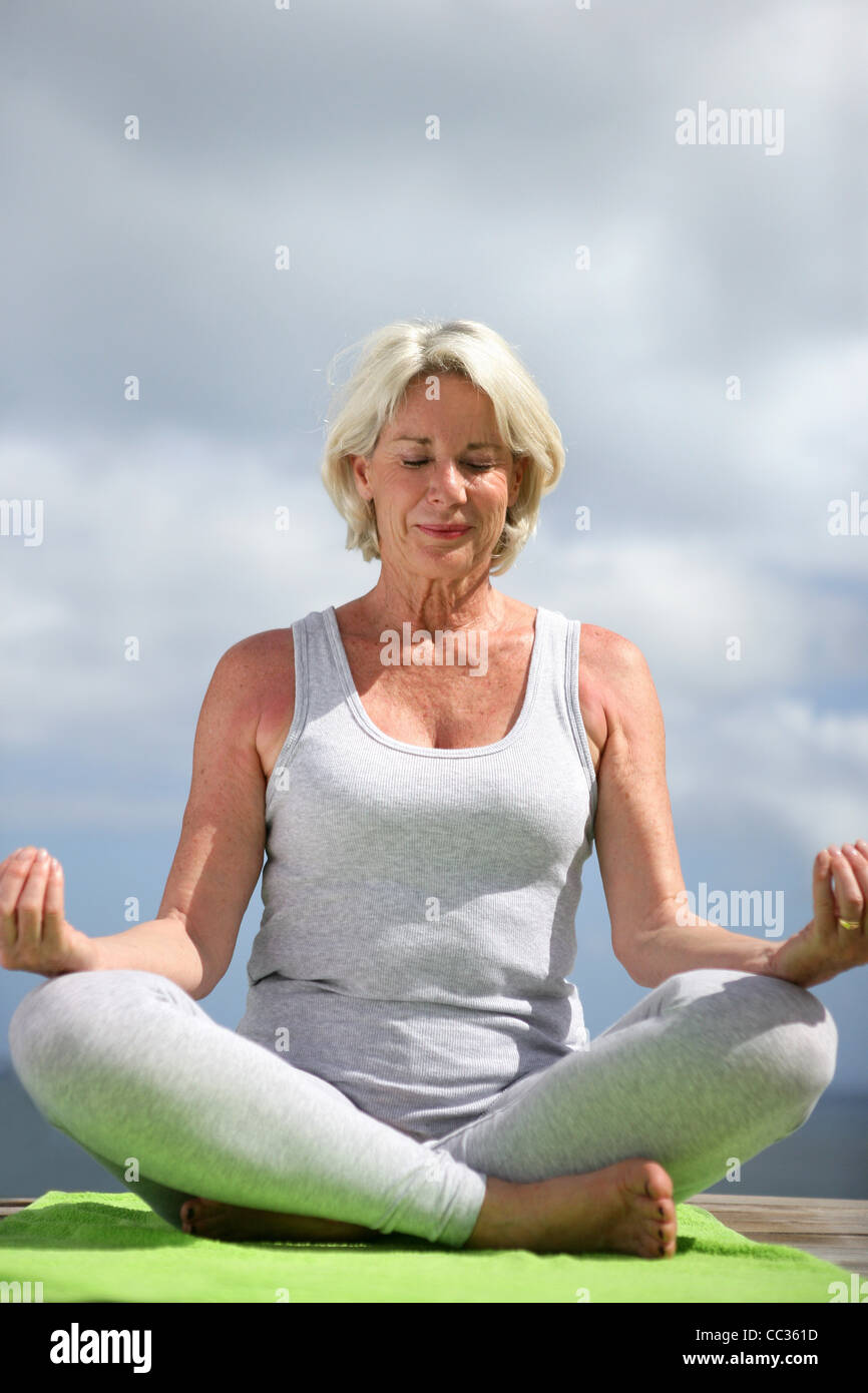 Middle-aged woman sat in yoga position Stock Photo - Alamy