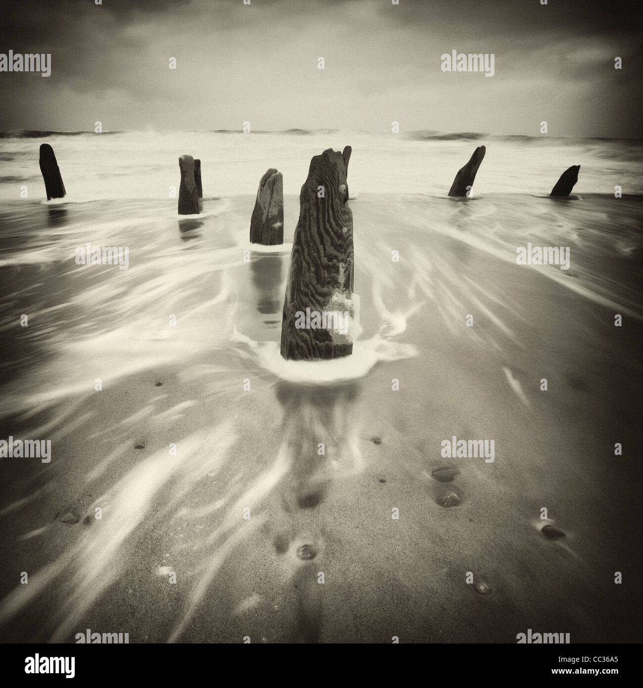 The tide moving over sand and around breakers Stock Photo - Alamy