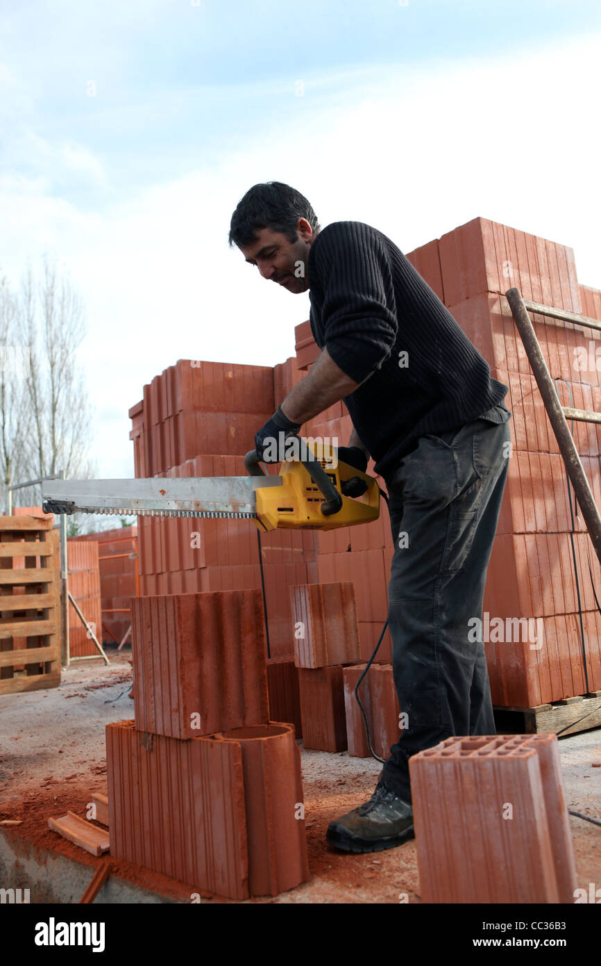 Man sawing through bricks Stock Photo - Alamy