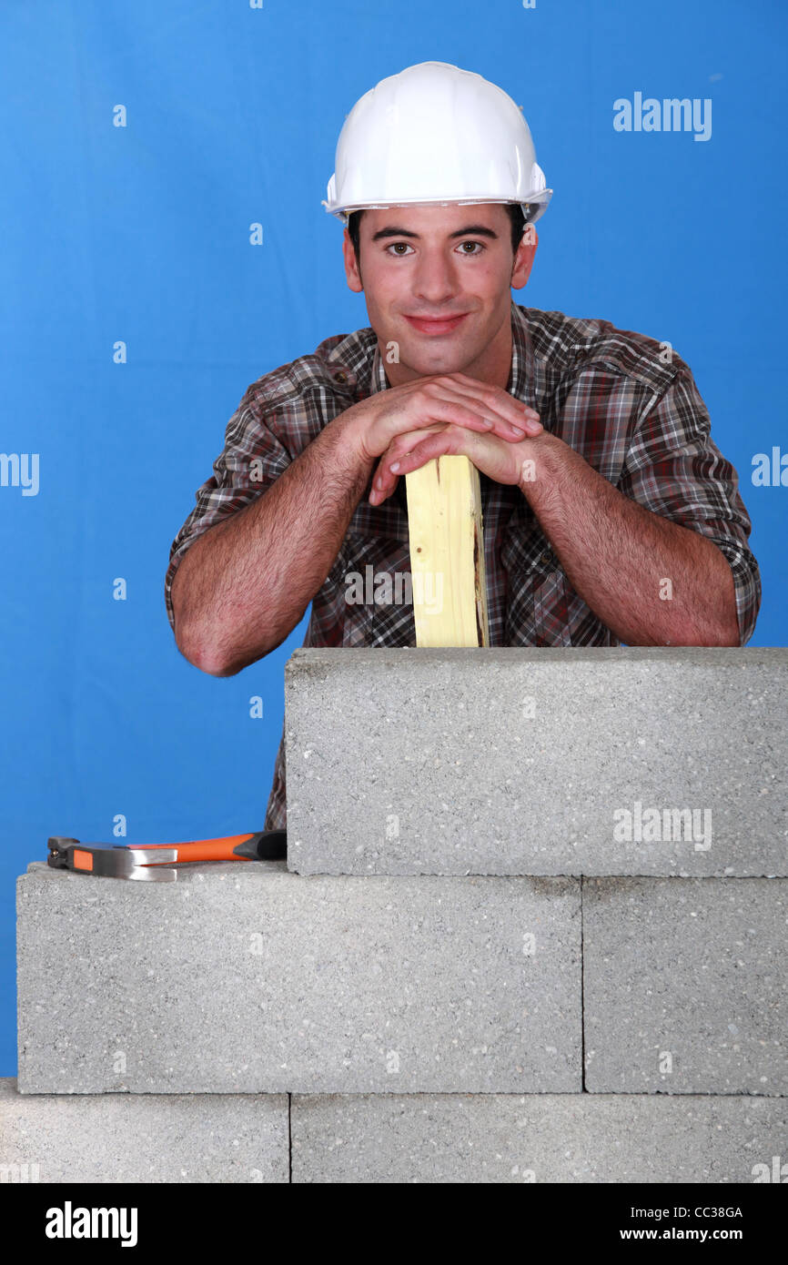 Smiling mason in front of blue background Stock Photo - Alamy