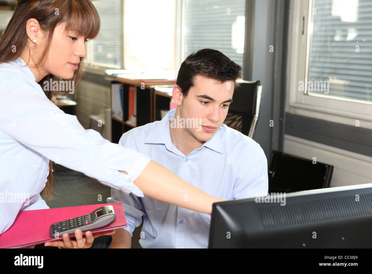 Woman explaining something on a computer to her colleague Stock Photo ...