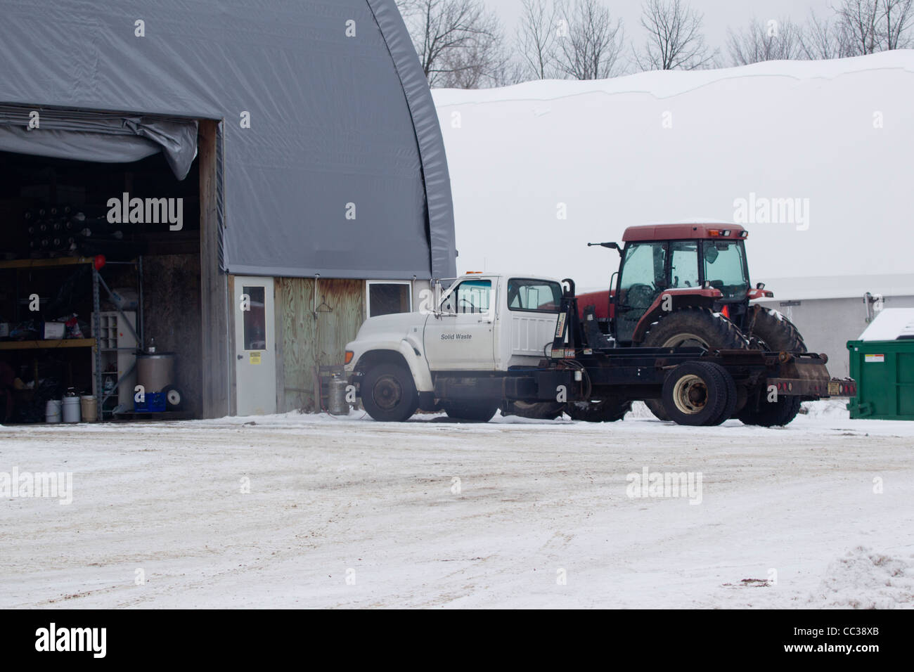 A truck and tractor parked outside a building at a waste recycling ...