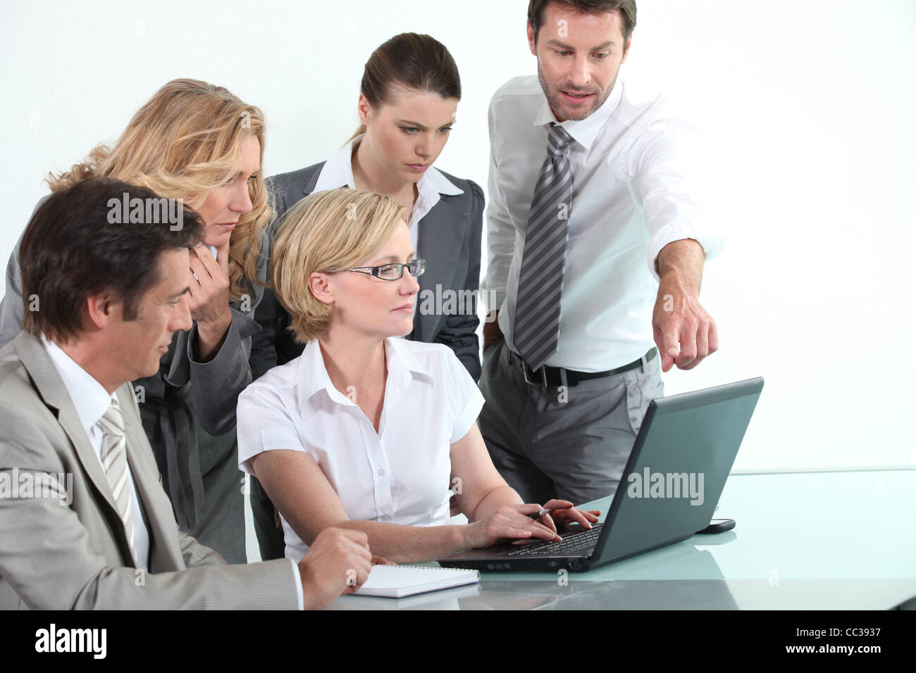 Business team sitting around a laptop computer Stock Photo - Alamy