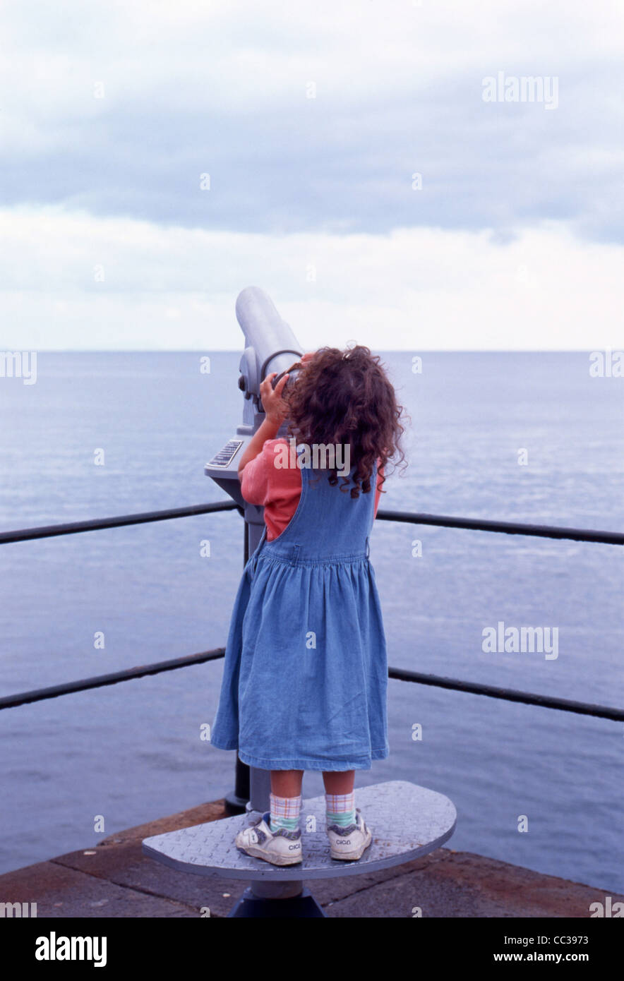 Rear view of a young caucasian child looking through telescope at ...
