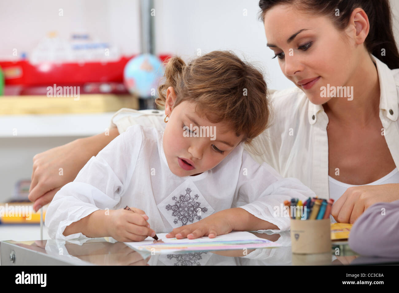 Teacher watching her pupil colouring a drawing Stock Photo - Alamy