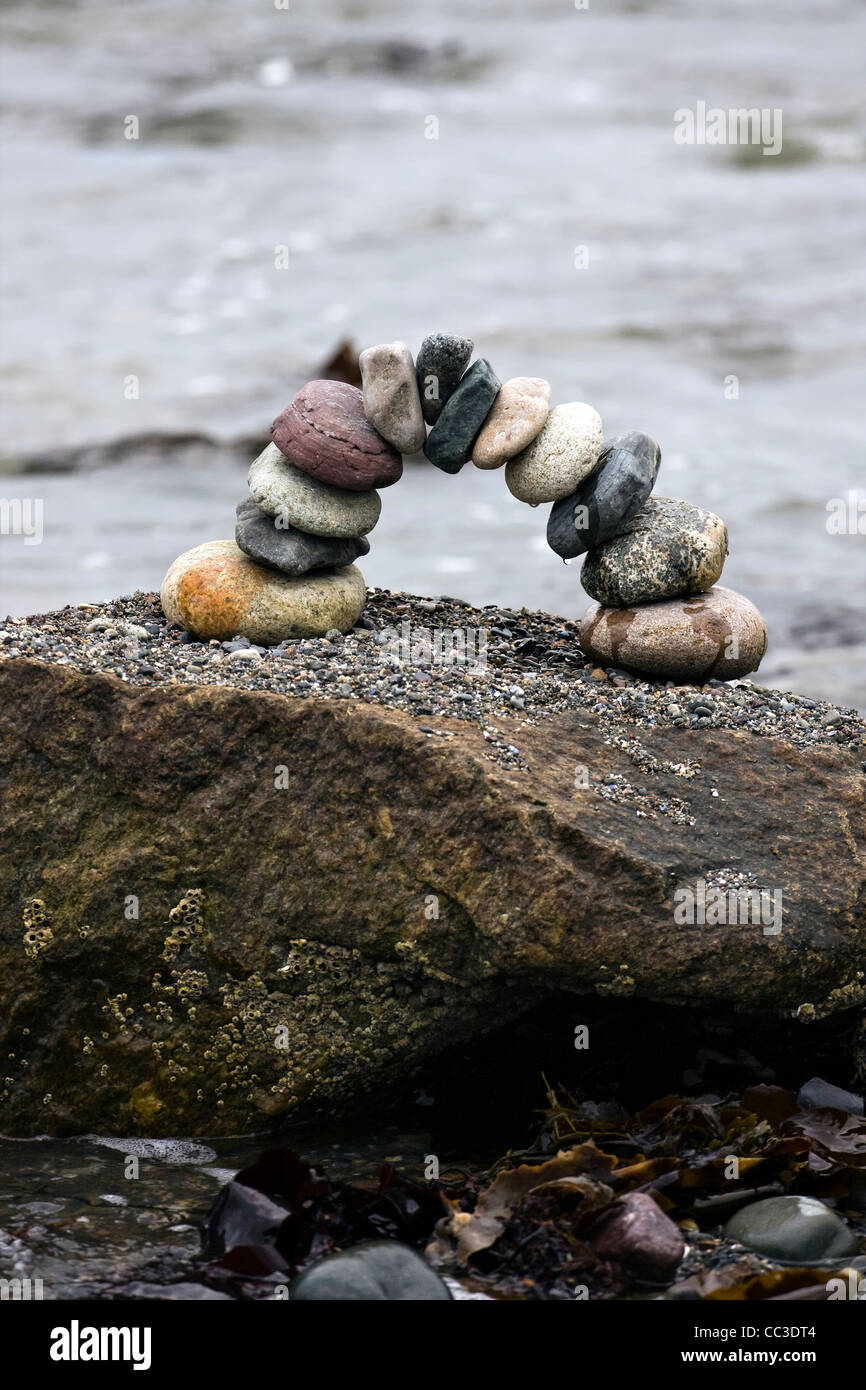 Balanced stones in a rock arch dripping water at the seaside after ...