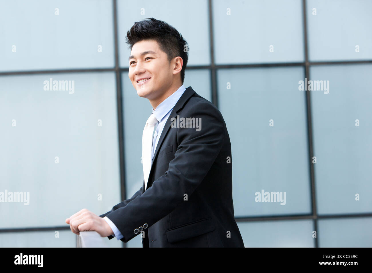 Smiling businessman leaning on the railing Stock Photo - Alamy