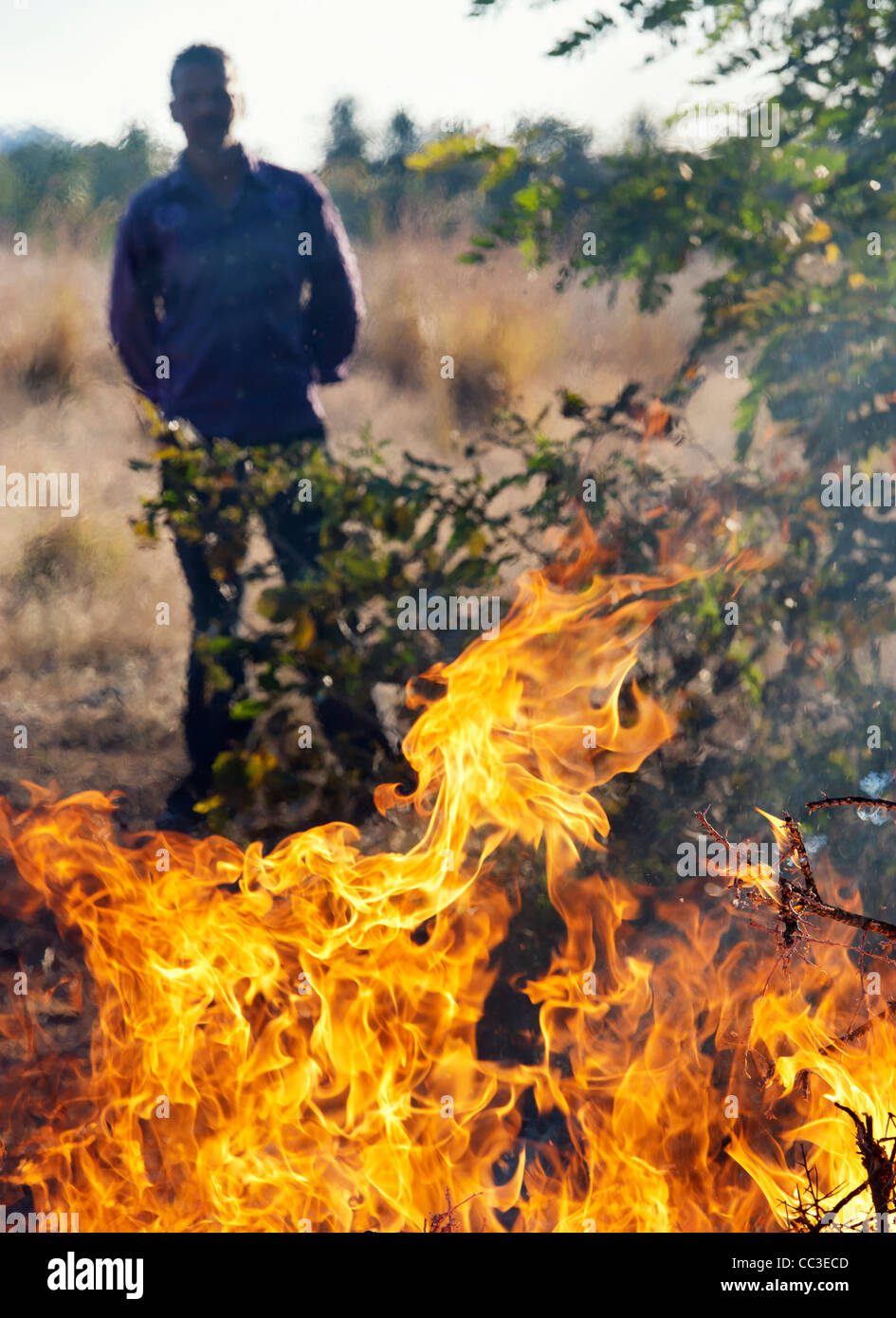 Indian man standing behind a fire in the indian countryside. Andhra ...