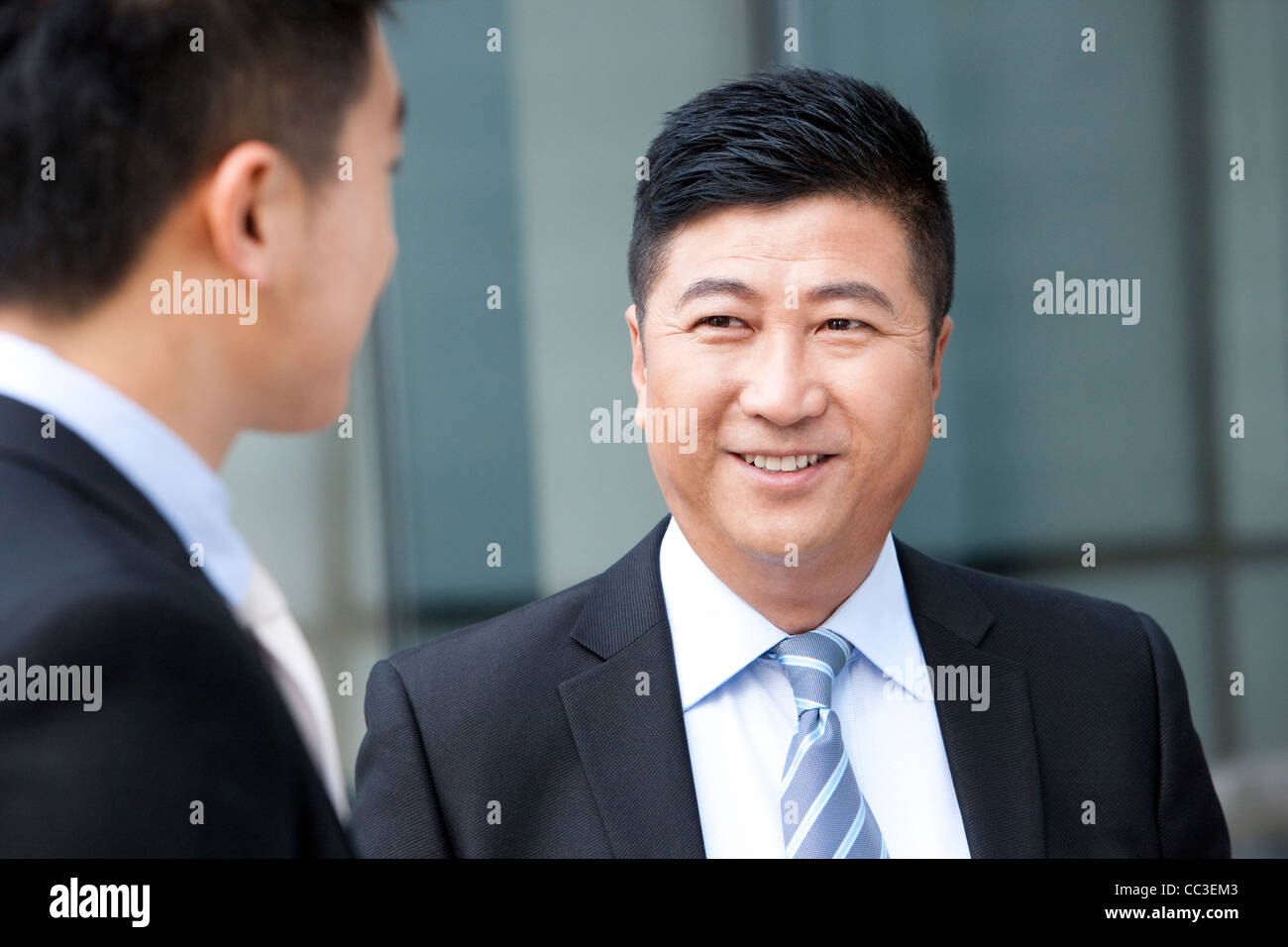 Standing smiling face to face communication building exterior hi-res ...