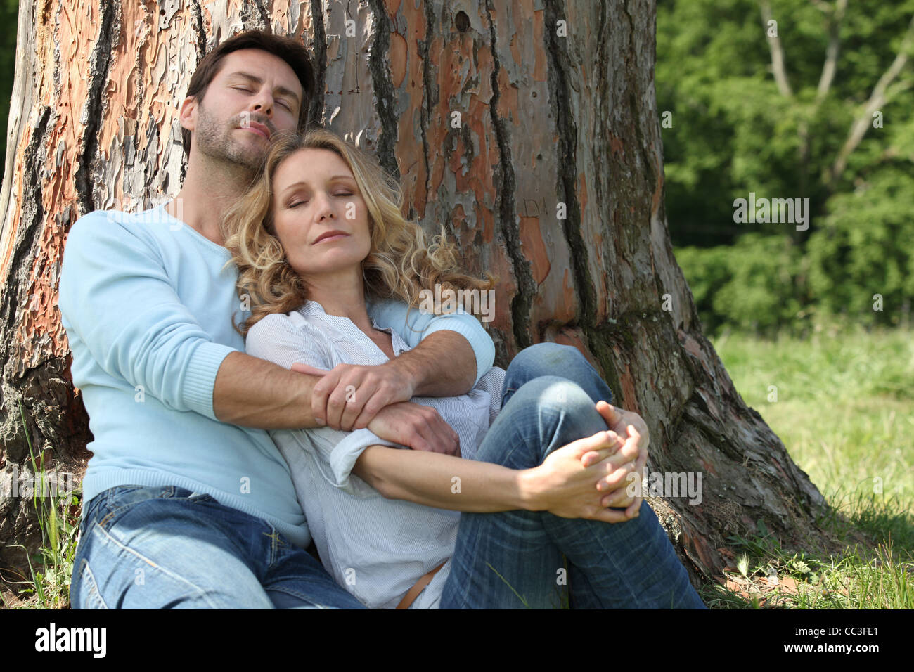 Couple sleeping under a tree Stock Photo - Alamy