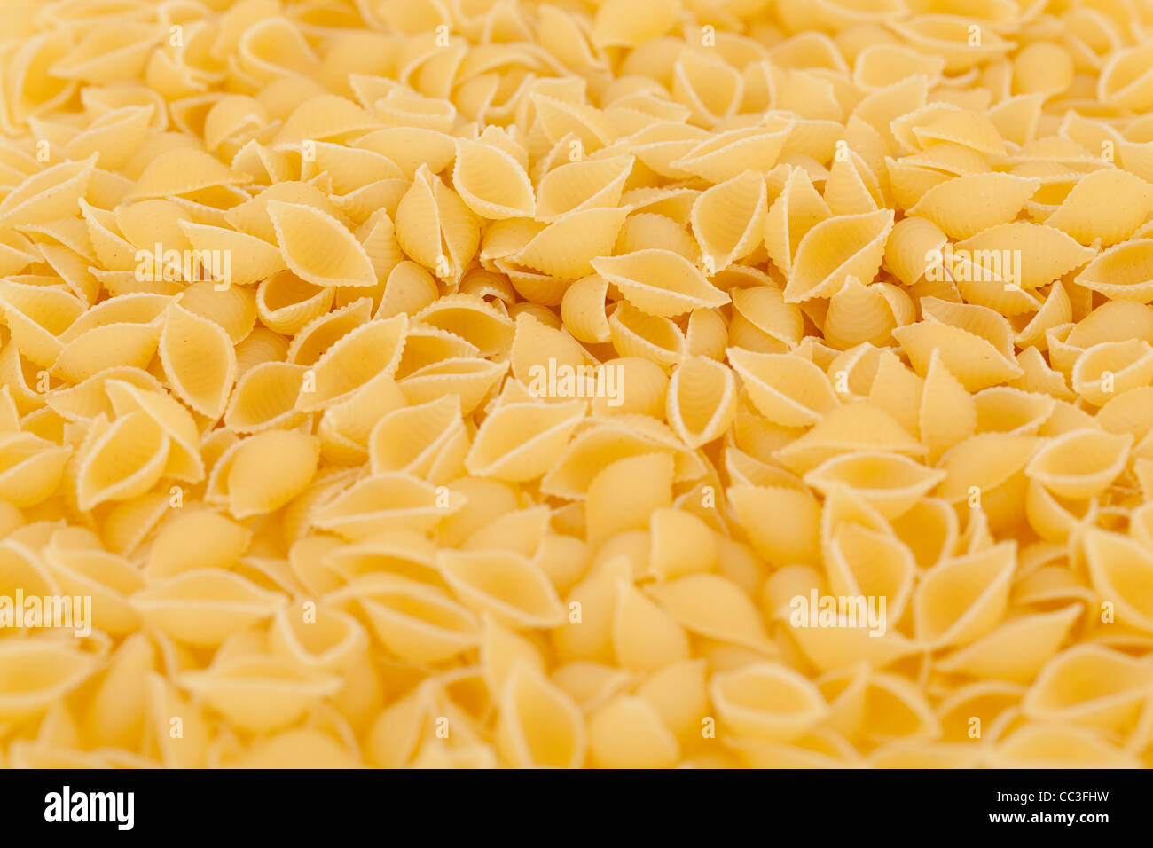 dry yellow pasta shells (conchiglioni) as background Stock Photo - Alamy
