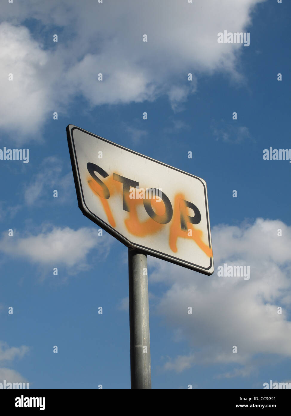 stop sign notice covered with graffiti with blue sky and white clouds ...