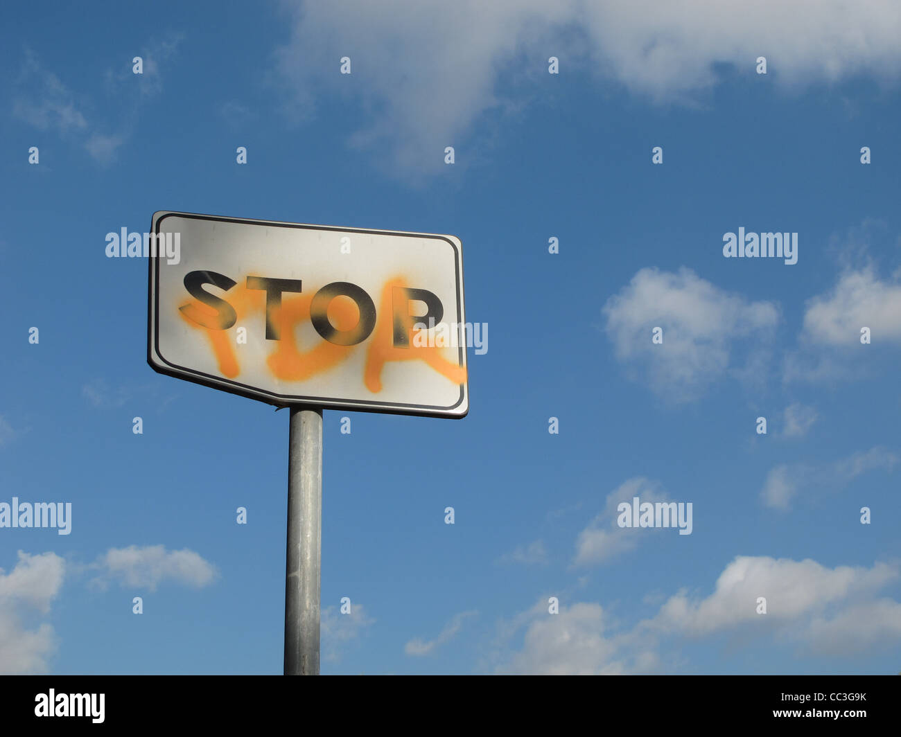 stop sign notice covered with graffiti with blue sky and white clouds ...