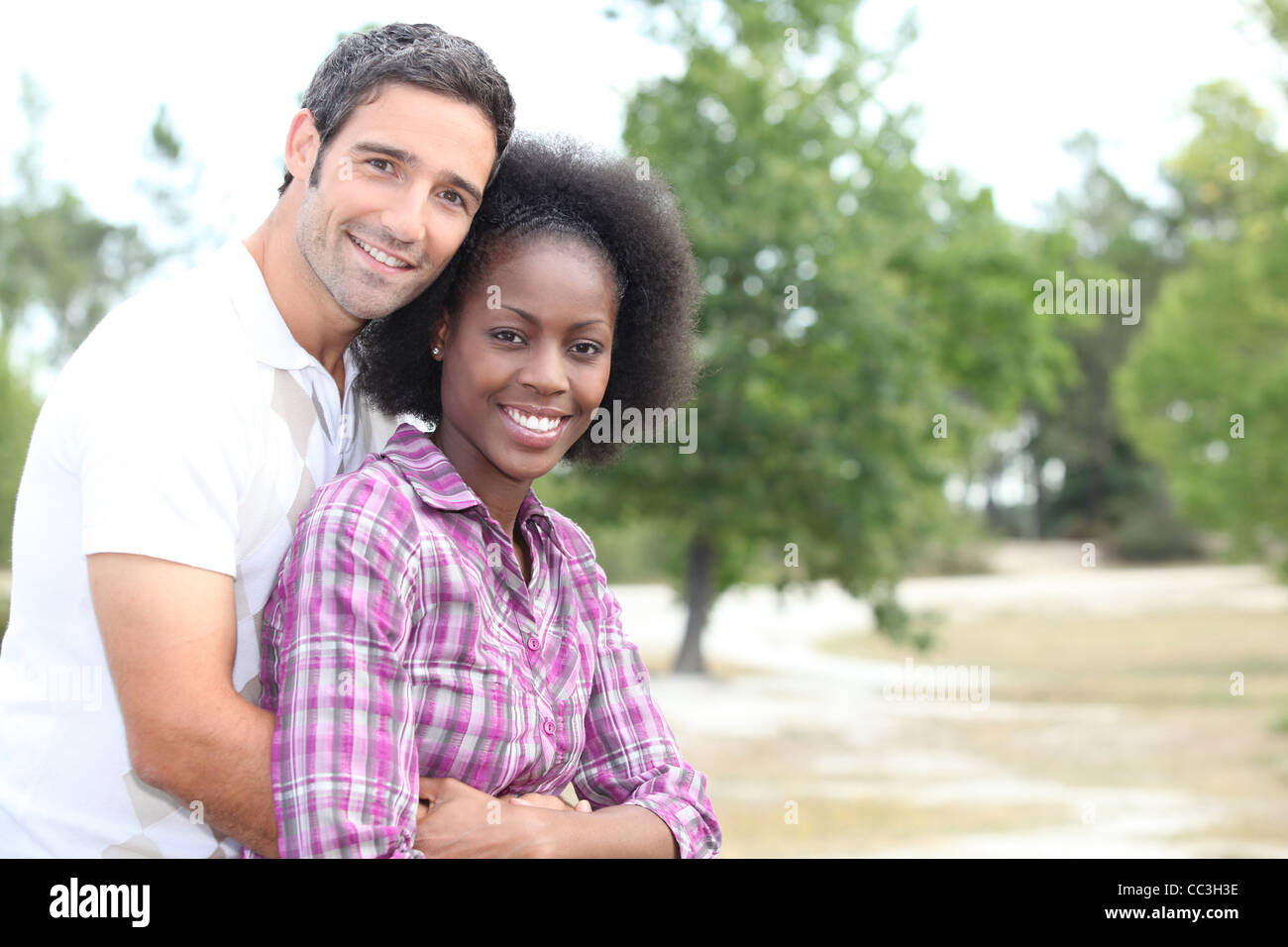 Mixed race couple hugging in the countryside Stock Photo - Alamy