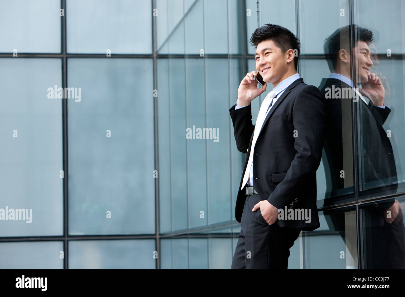 Businessman on the phone leaning against the wall Stock Photo - Alamy