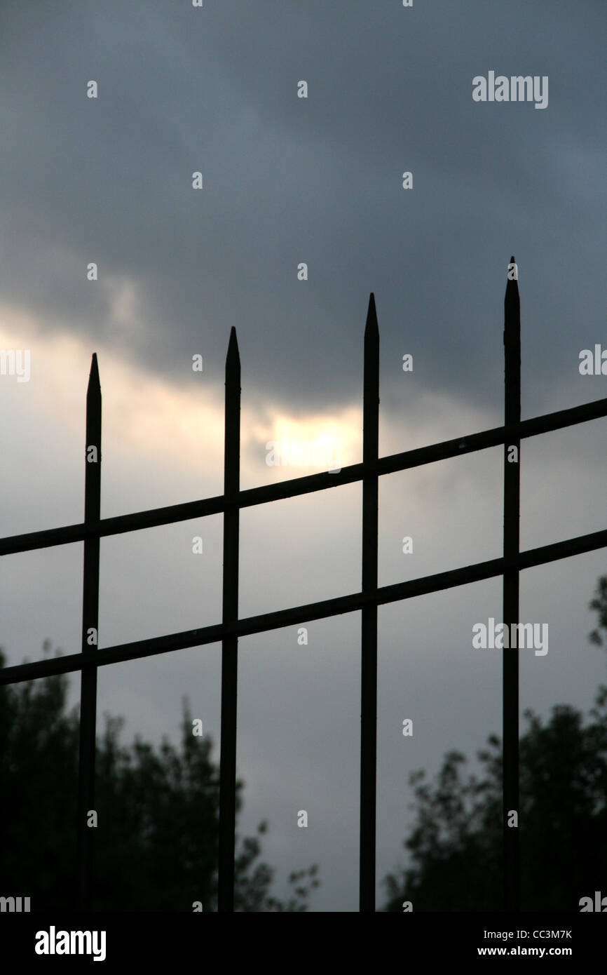 High fence with sharp spikes against dark Stock Photo - Alamy