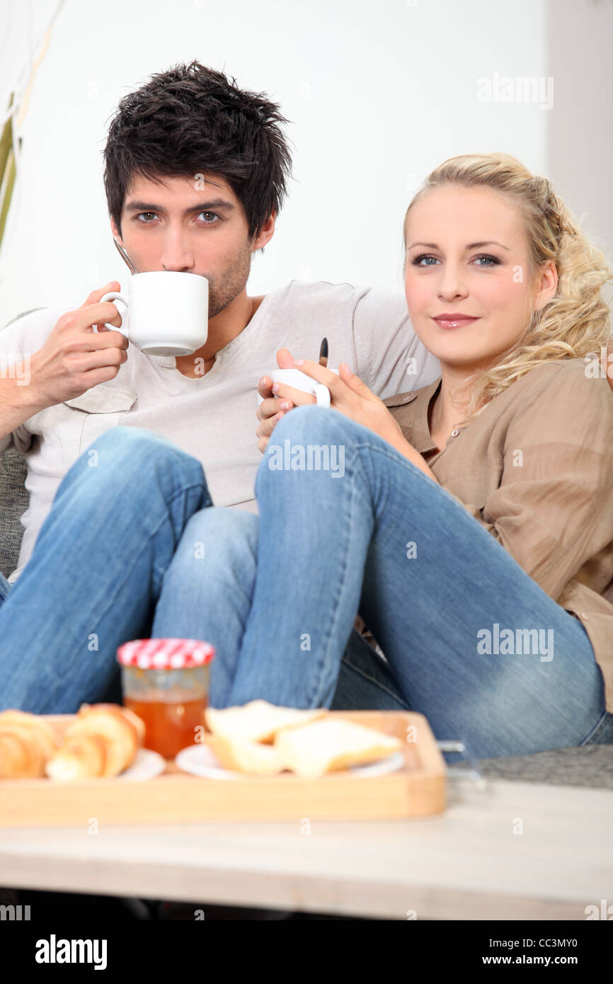 Couple having breakfast on the sofa Stock Photo - Alamy