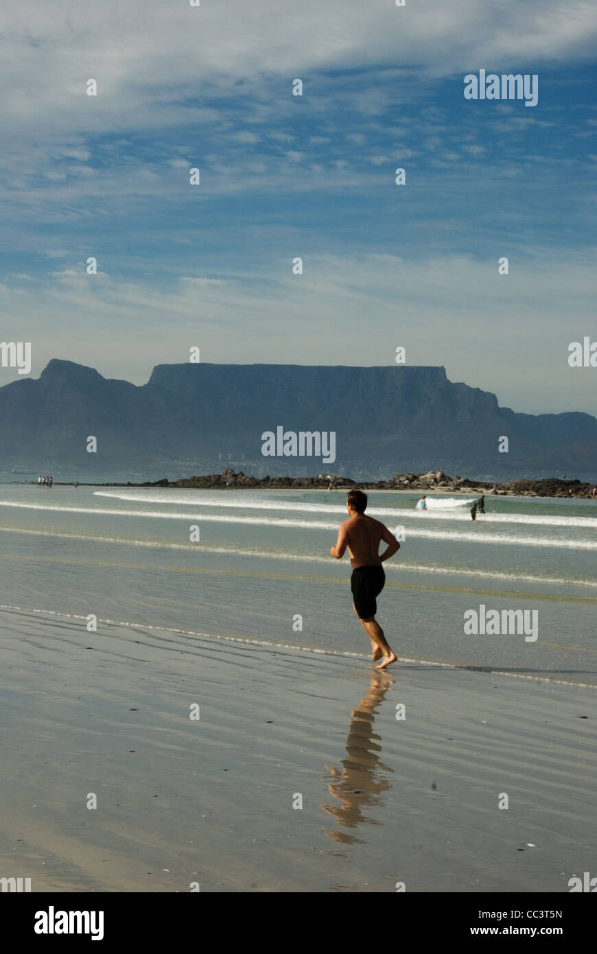 Man running on beach with table mountain in the background Stock Photo ...