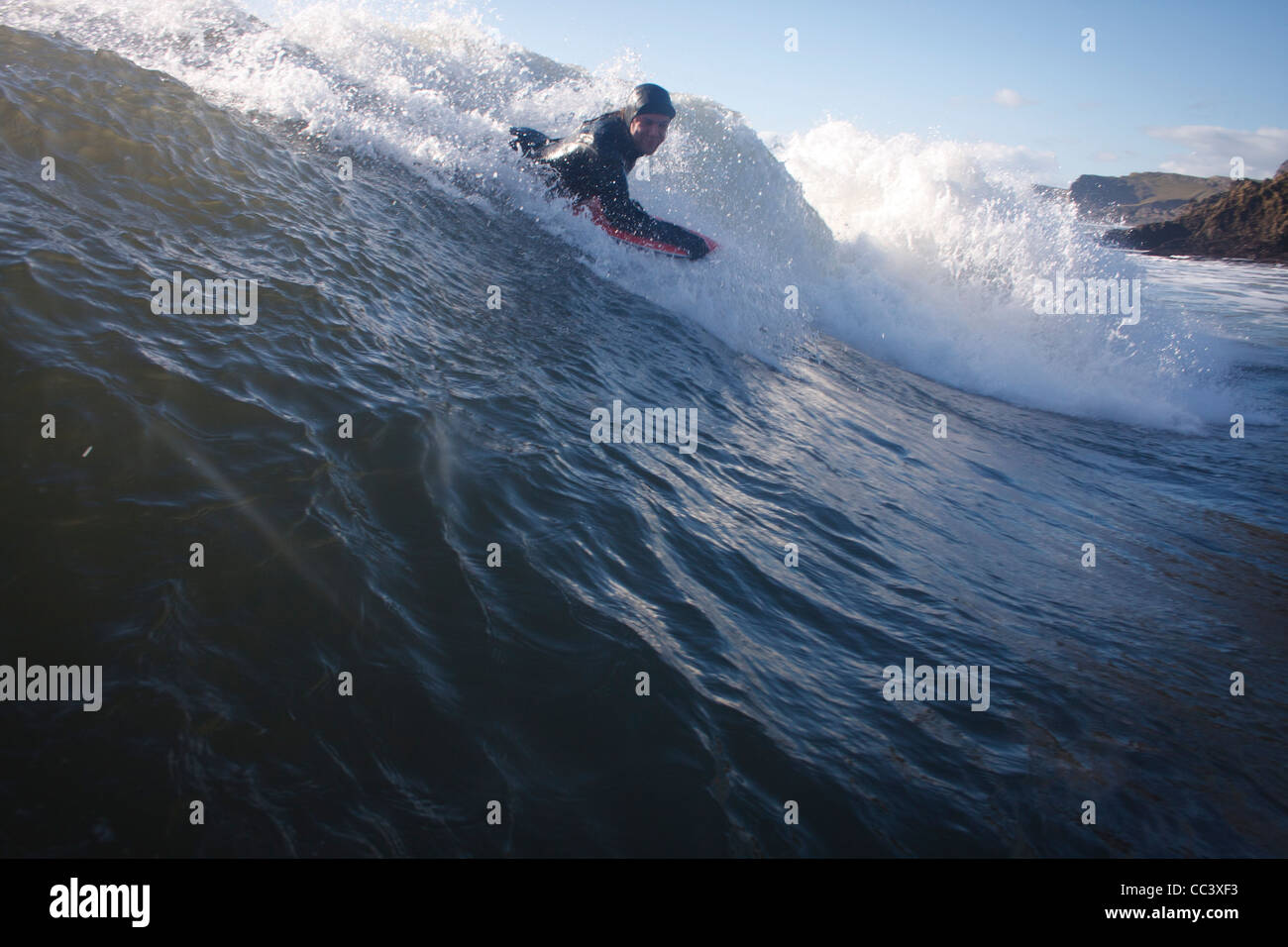A surfer rides the waves at a remote Gower Reef Break, Gower, Swansea ...