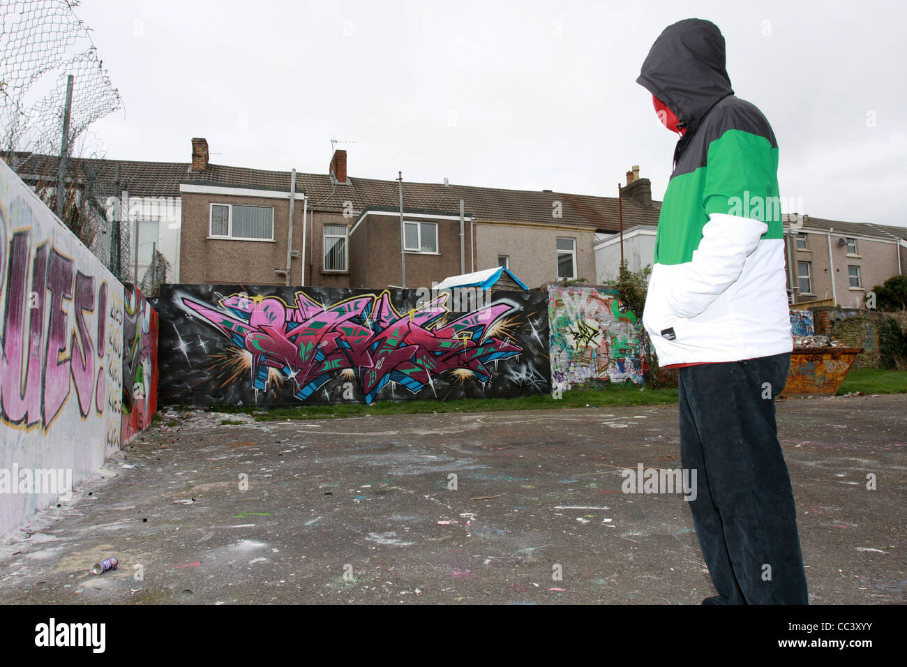 A graffiti writer poses anonymously wearing a hooded jacket infornt of ...