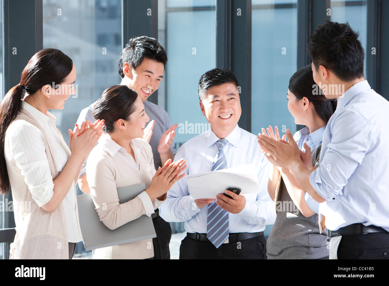 Businesspeople clapping and congratulating team leader Stock Photo - Alamy